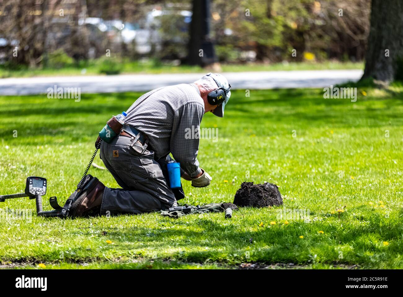 Man using a metal detector in a park to look for items buried ...