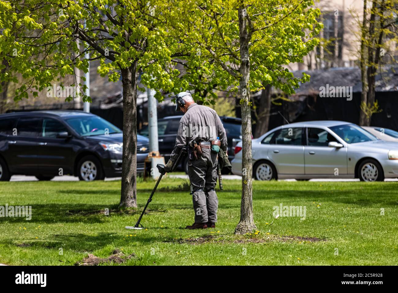 Man using a metal detector in a park to look for items buried ...