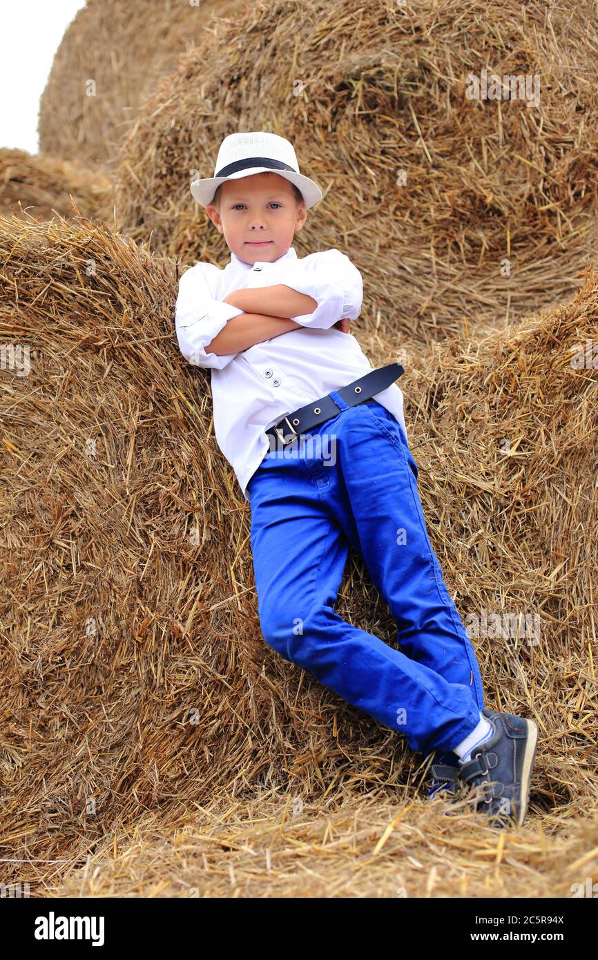 A cute boy is high under the sky on a haystack in the hay season Stock ...