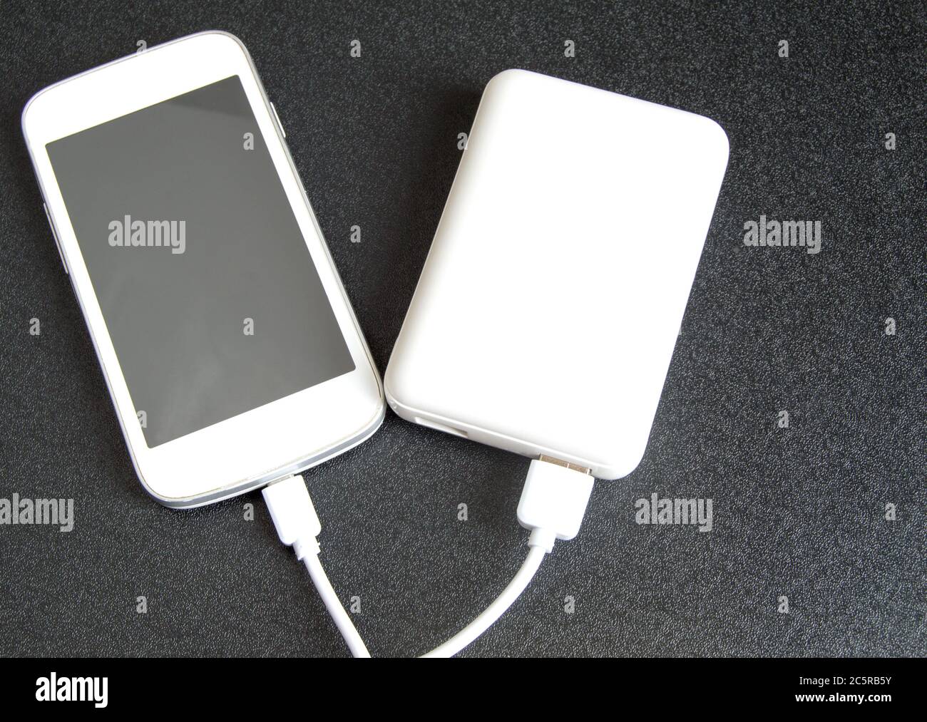 A white phone with a black screen and a copy of space is charged using ...