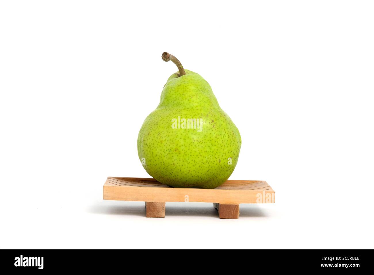 Single fresh Packham pears fruit above square wooden plate isolated on ...