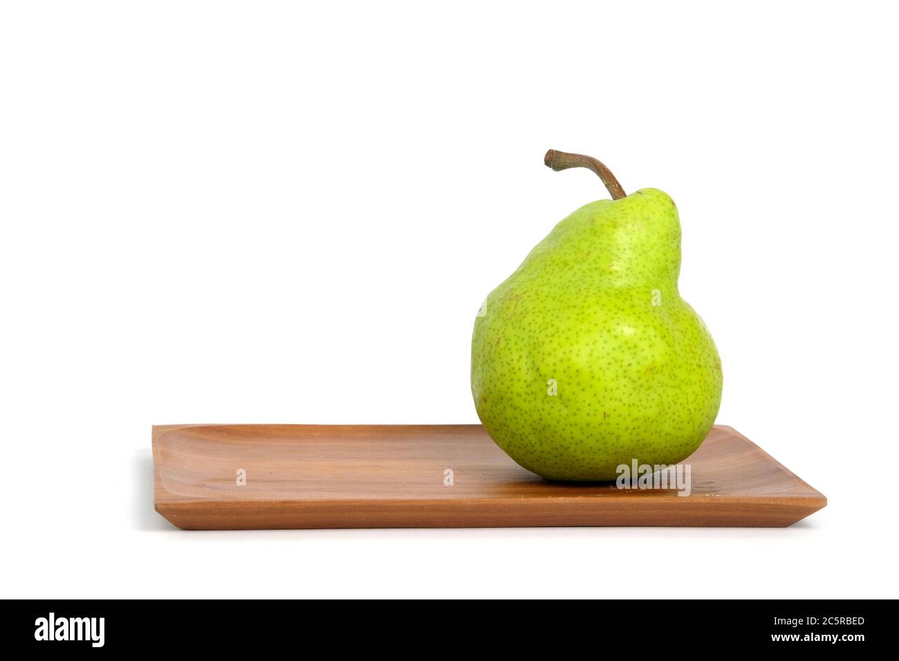 Single fresh Packham pears fruit above square wooden plate isolated on ...