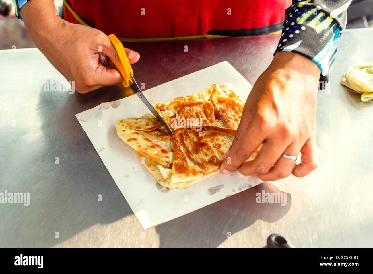 Hands of street vendor cooking Thai style sweet roti bread on steel ...