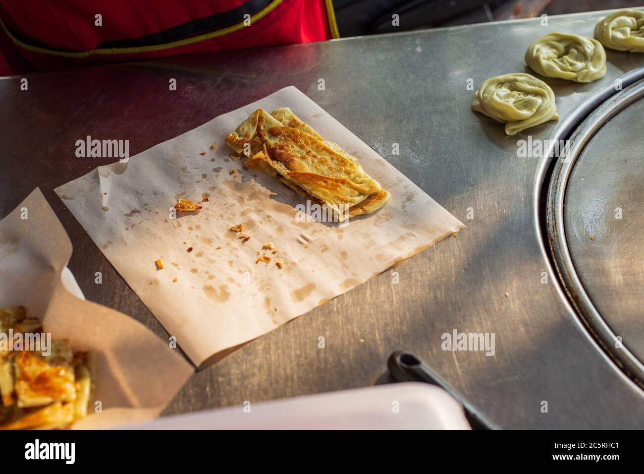 Hands of street vendor cooking Thai style sweet roti bread on steel ...