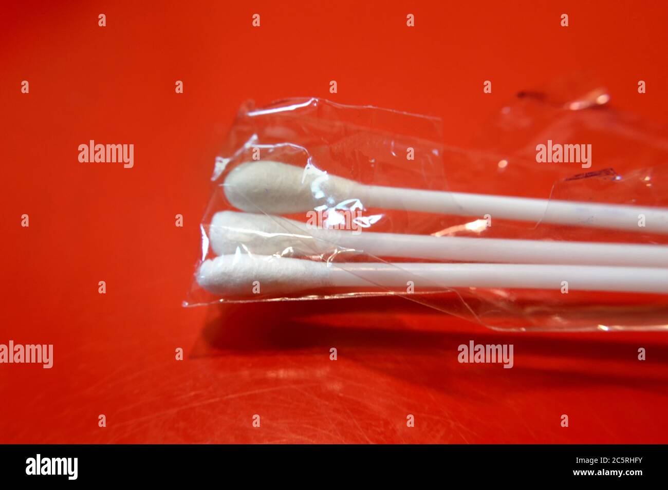 Cotton sticks in folia on red texture background Stock Photo - Alamy