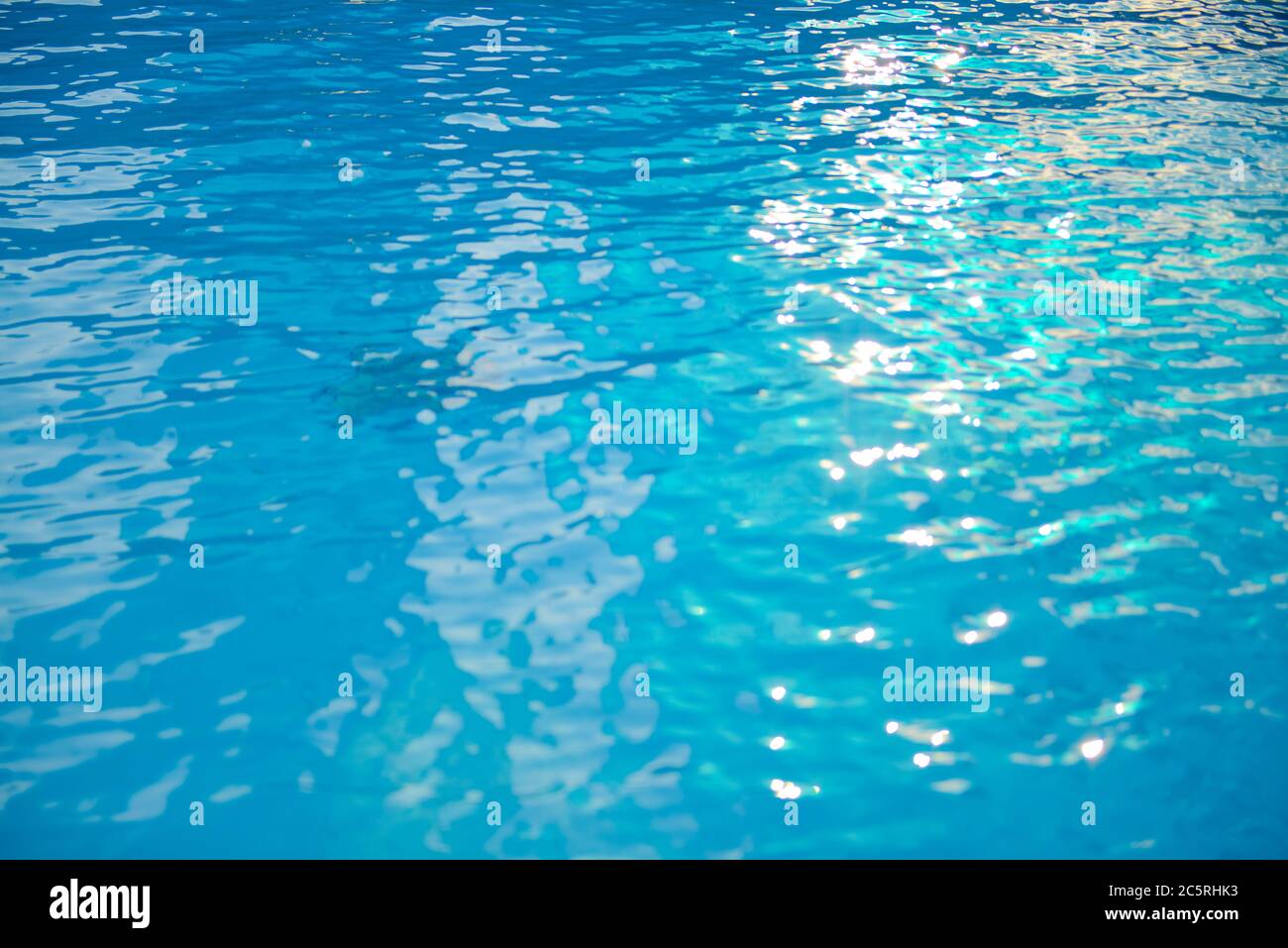 Soft focus bokeh light effects over a rippled, blue water background in ...