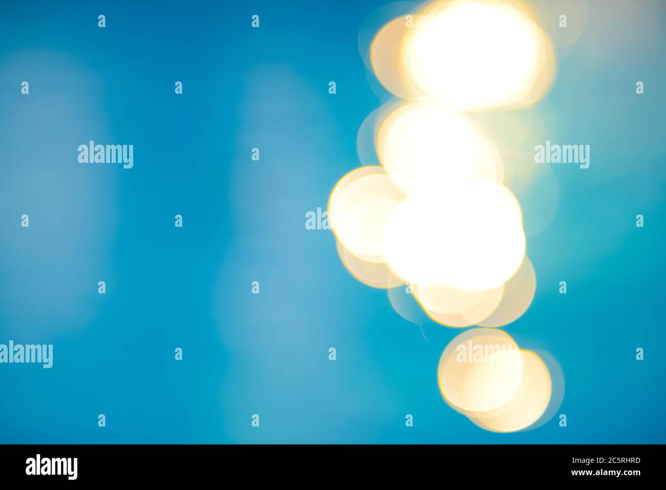 Soft focus bokeh light effects over a rippled, blue water background in ...