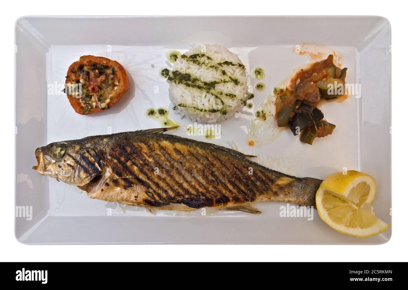 Roasted fish with rice, lemon and vegetables on the dish isolated on ...