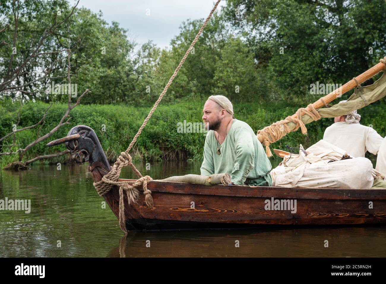 A group of men in clothes of the Viking era (9-11 century) rowing on ...