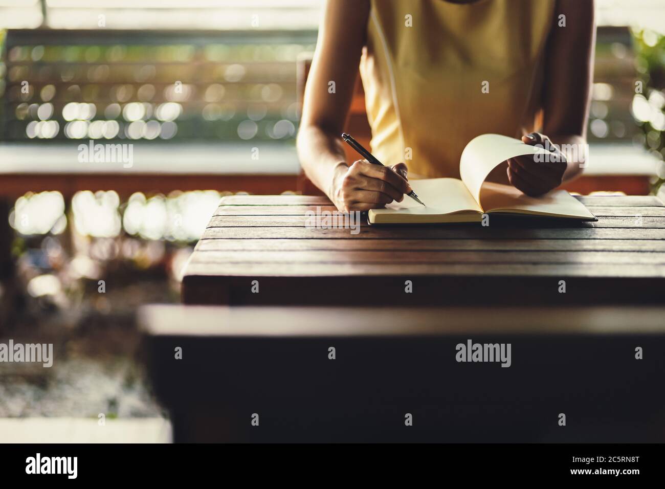 Hand hold pen and writing a book on the table Stock Photo - Alamy