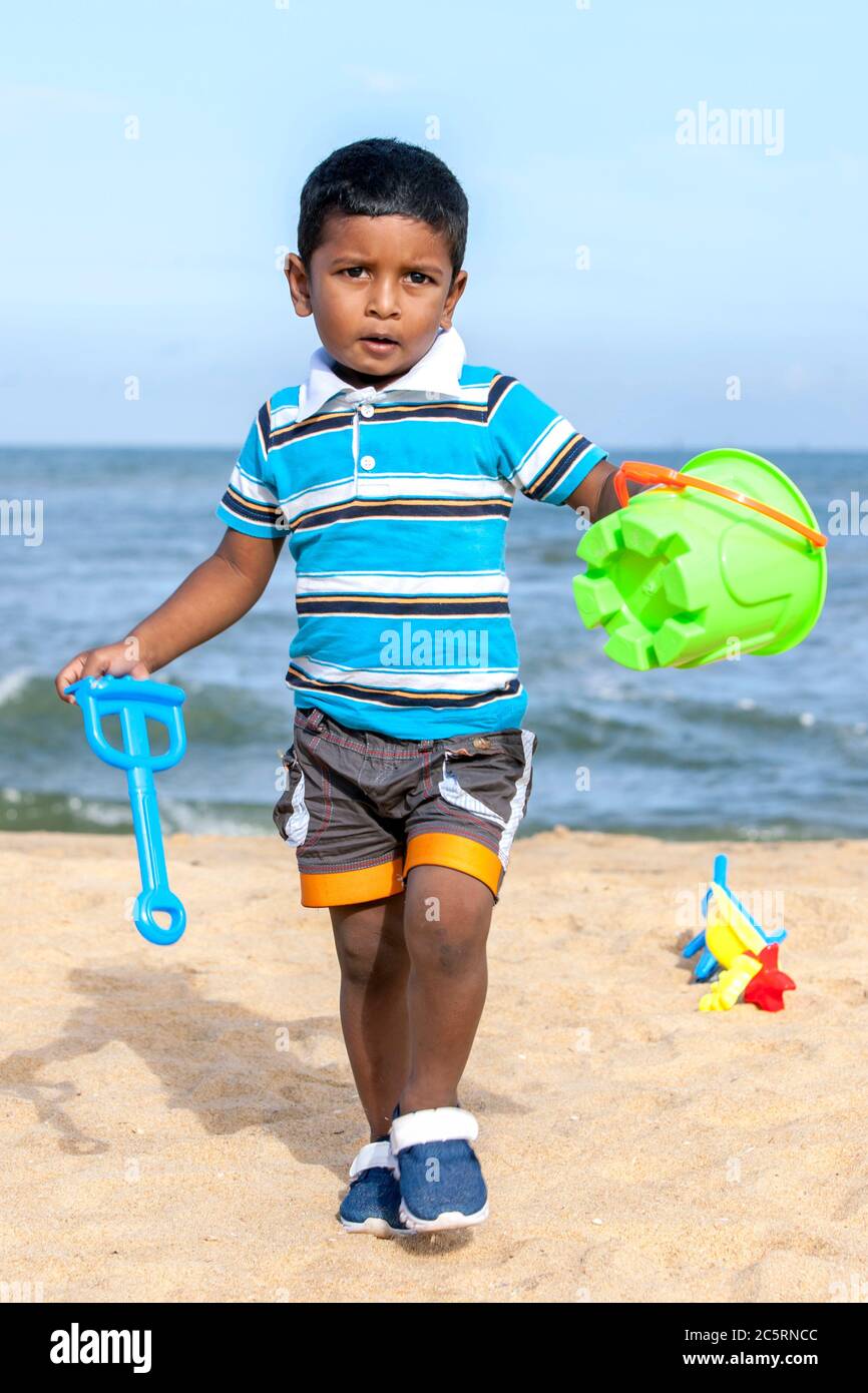A Sri Lankan boy playing with a plastic bucket and spade on Negombo ...