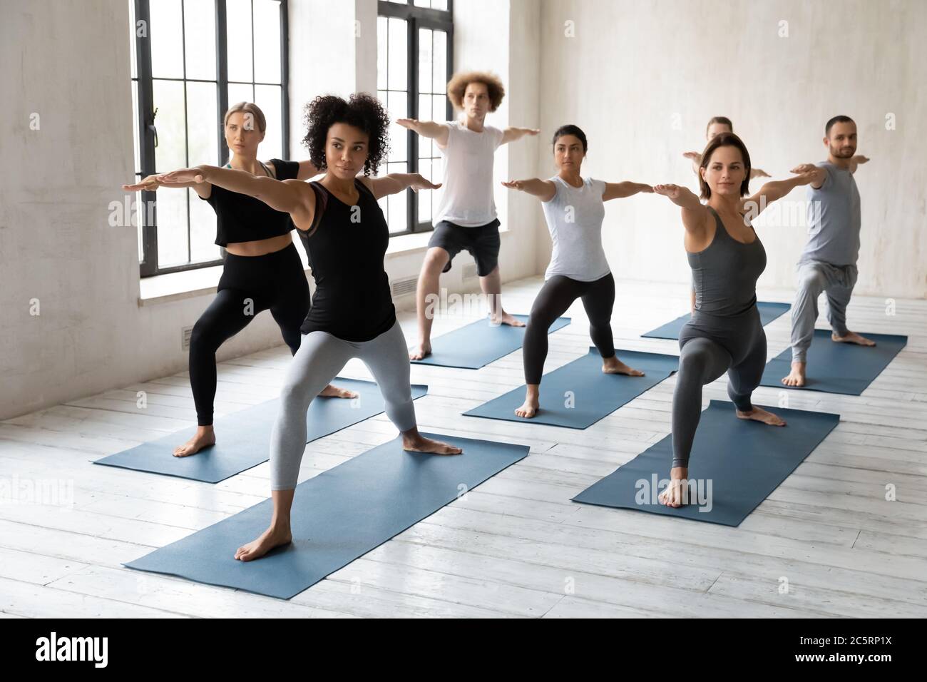 Happy mixed race people standing in warrior II pose Stock Photo - Alamy