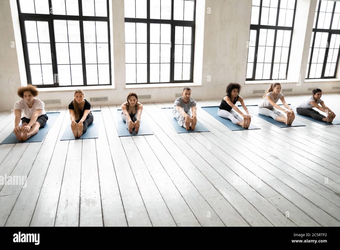 Young motivated mixed race people sitting in forward bend pose Stock ...