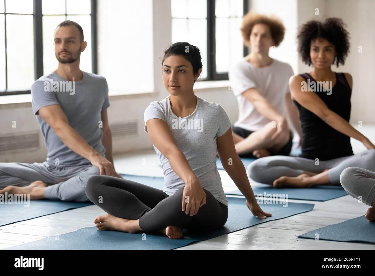 Young mixed race people doing simple seated twist exercise Stock Photo ...
