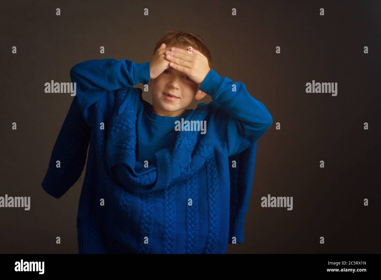 Studio portrait of a dark-haired boy with a short haircut in a blue t ...