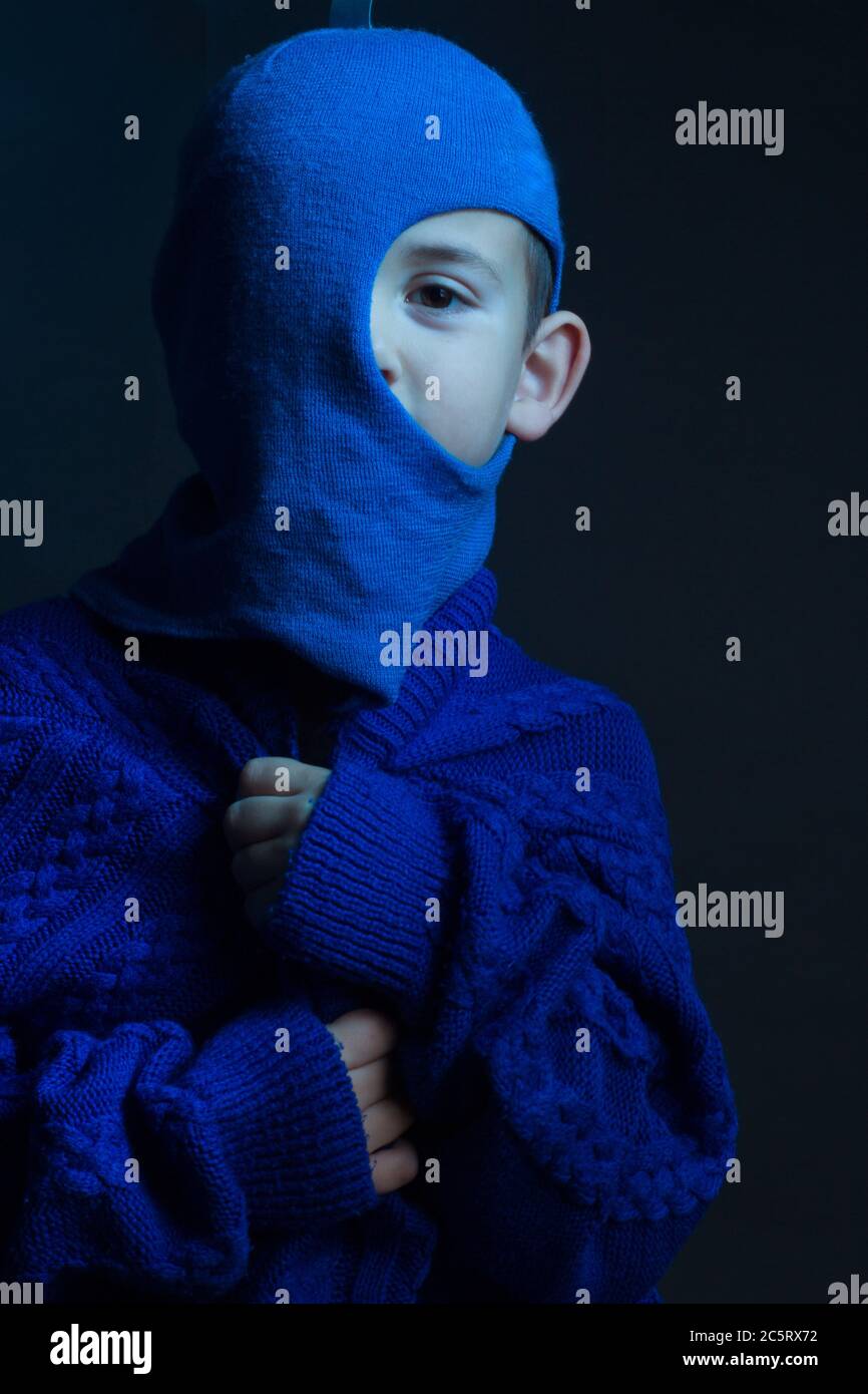Studio portrait of a boy in a blue Balaclava, turned on the left ear ...