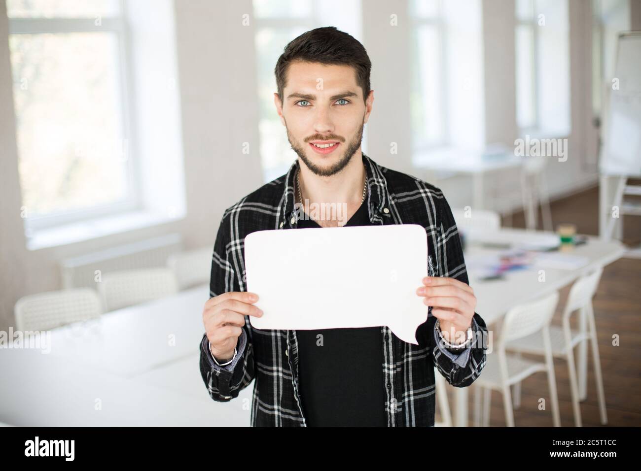 Young smiling man in black short dreamily looking in camera while ...