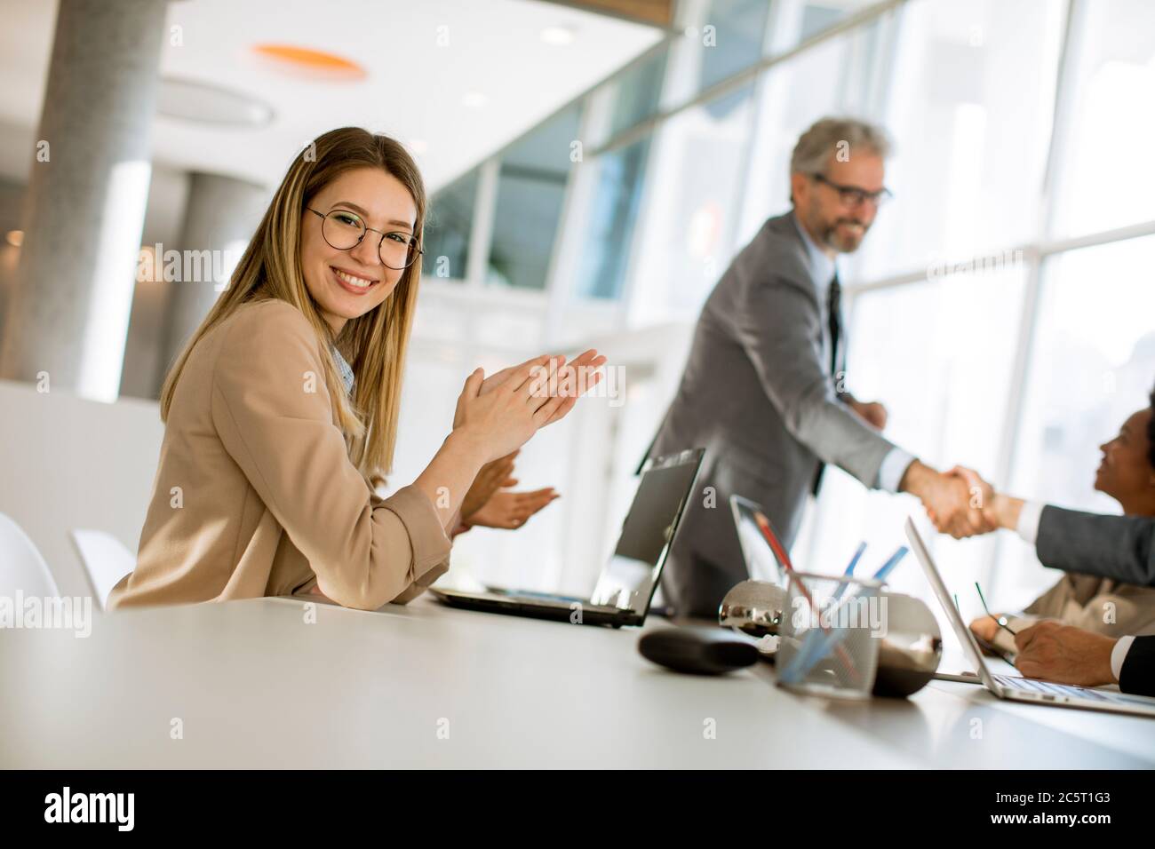 Pretty young woman clapping hands after successful business meeting in ...