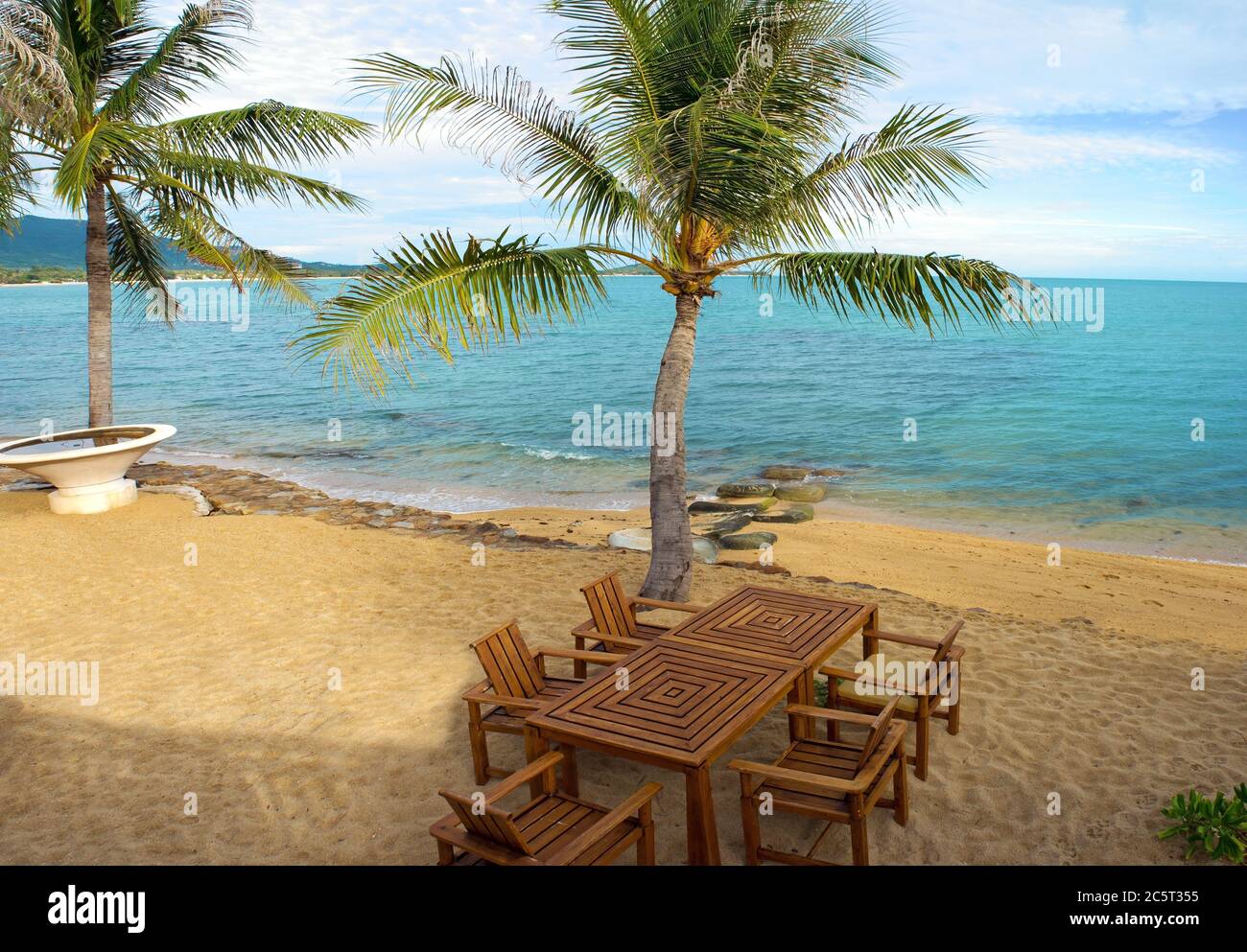 Table and chairs on sand beach with blue ocean Stock Photo - Alamy
