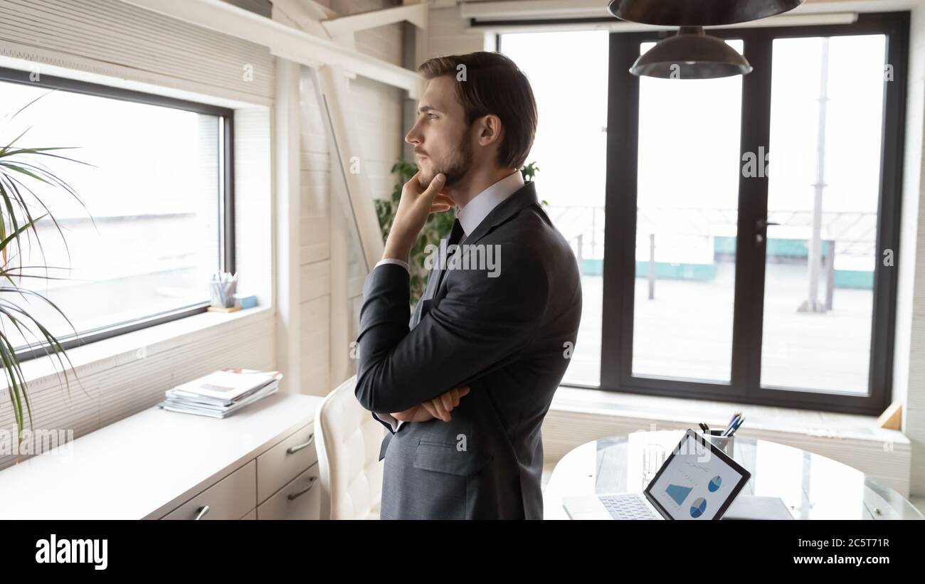 Pensive young male boss look in distance thinking Stock Photo - Alamy