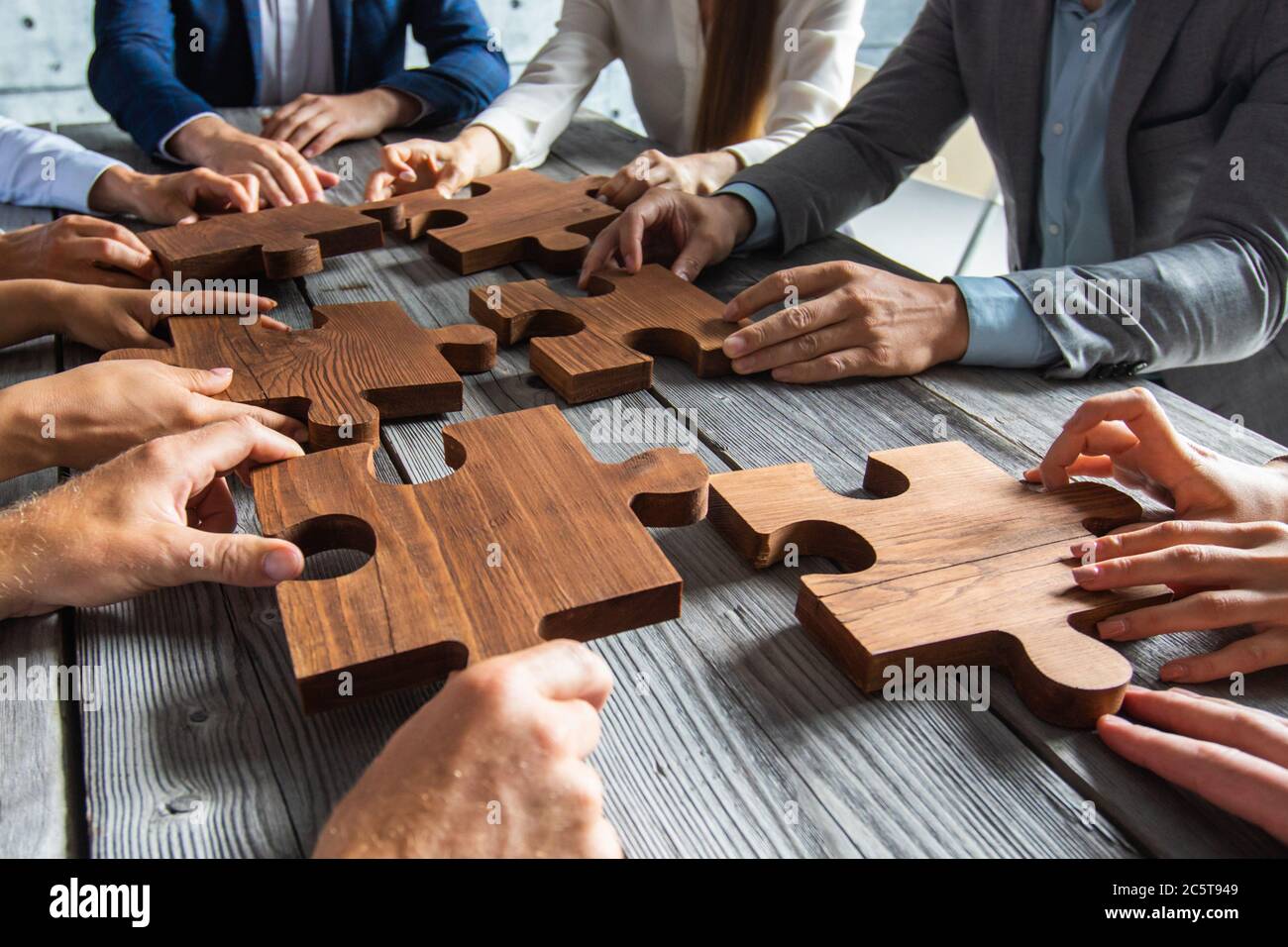 Business people team sitting around meeting table and assembling wooden ...