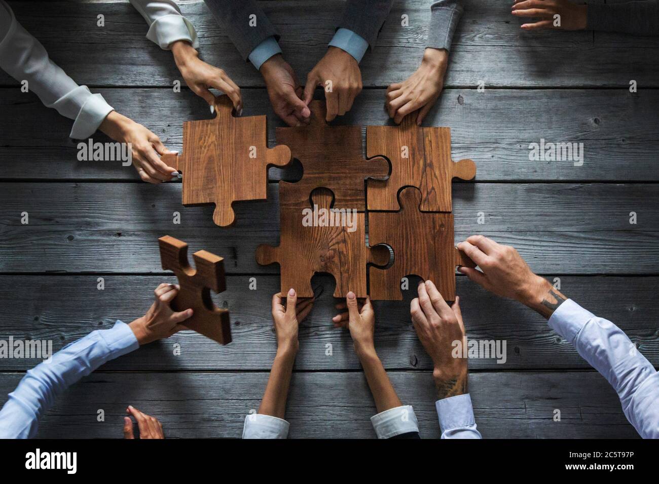 Business people team sitting around meeting table and assembling wooden ...