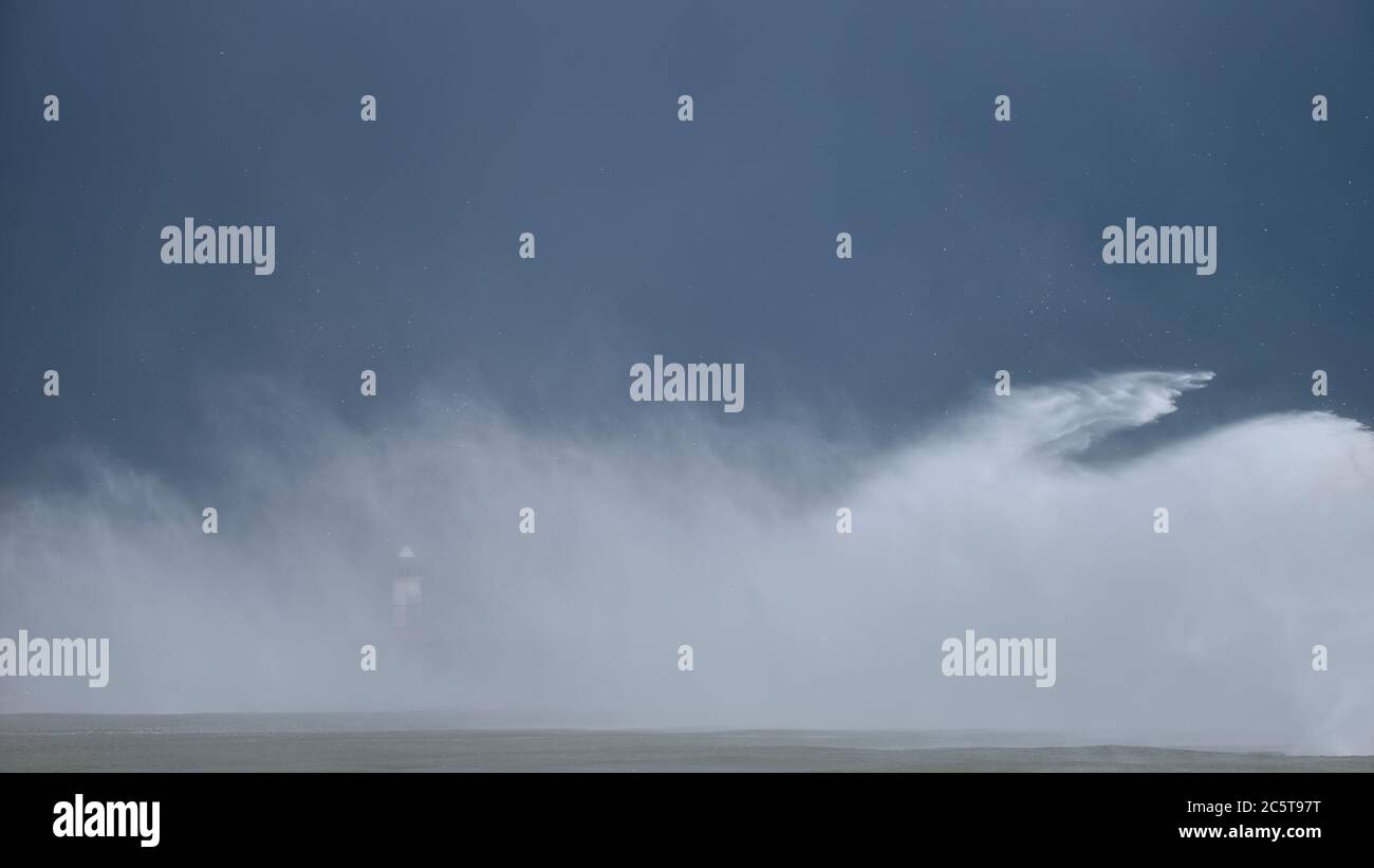 Huge waves crash over harbour wall onto lighthouse during huge storm on ...