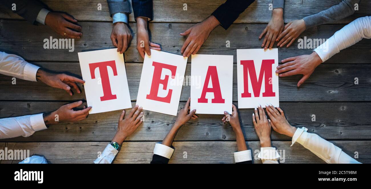 Business people holding TEAM letters printed on paper Stock Photo - Alamy
