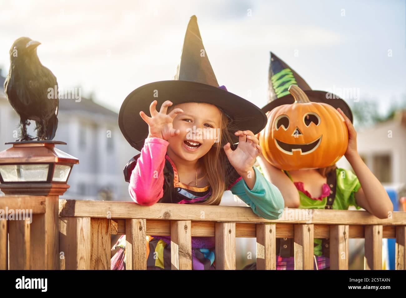 Happy Halloween! Two cute little laughing girls in witches costumes are ...
