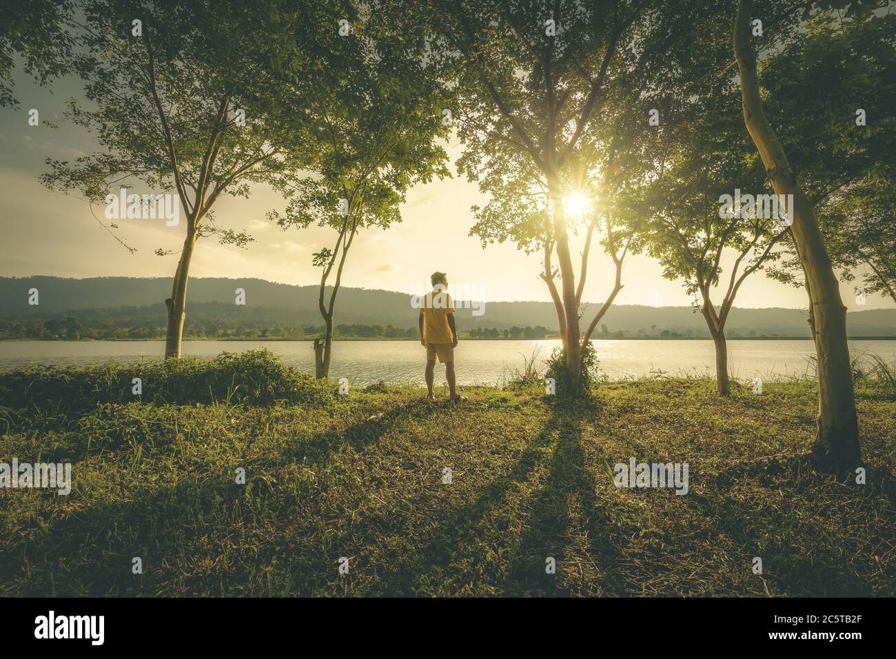 A man stand in the forest and near the water with mountain back Stock ...