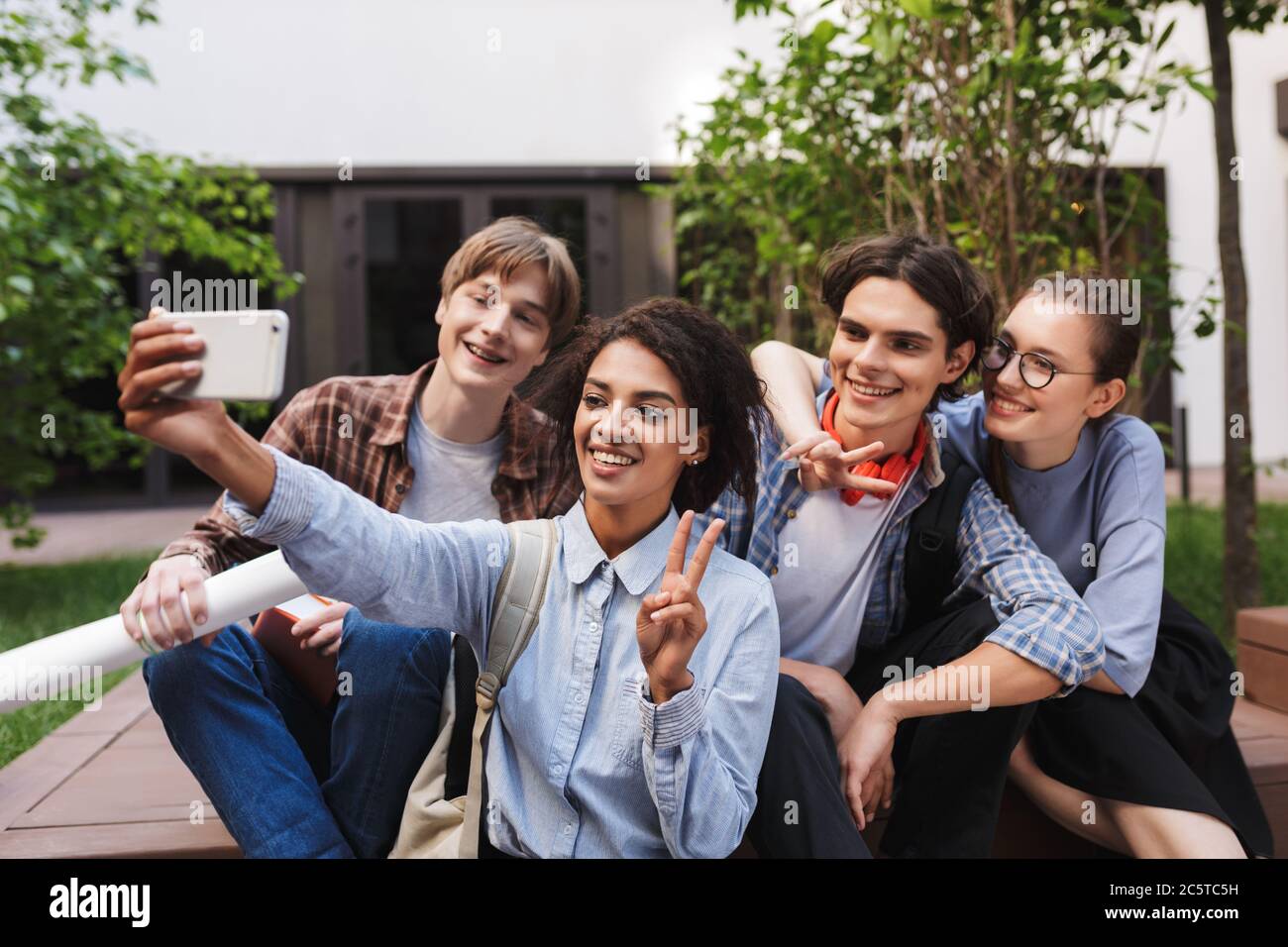 Group of young smiling students sitting and taking cute photos on ...