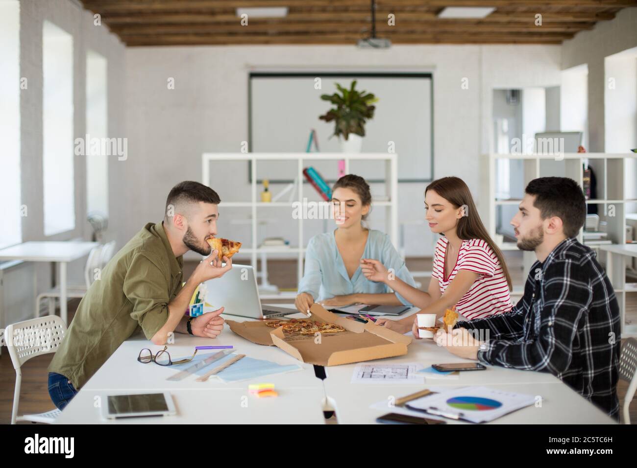 Group of young creative people eating pizza together pending time at ...