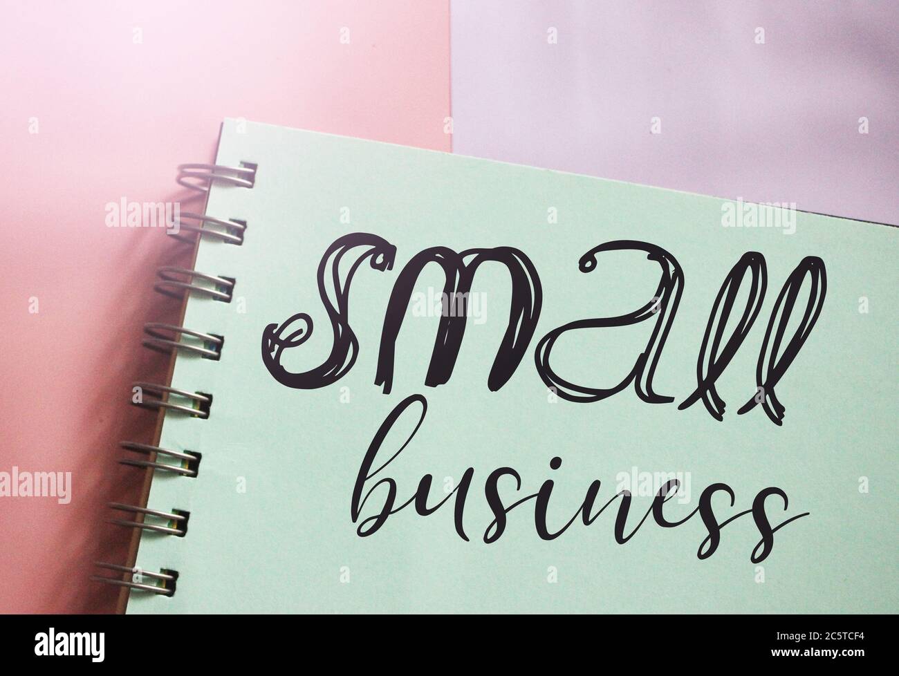 Small business words lettering on mint color page in copybook on pink ...