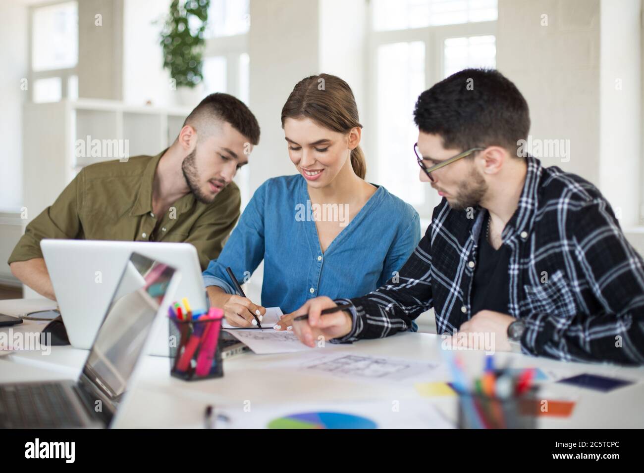 Young creative people with laptop working on project together. Group of ...