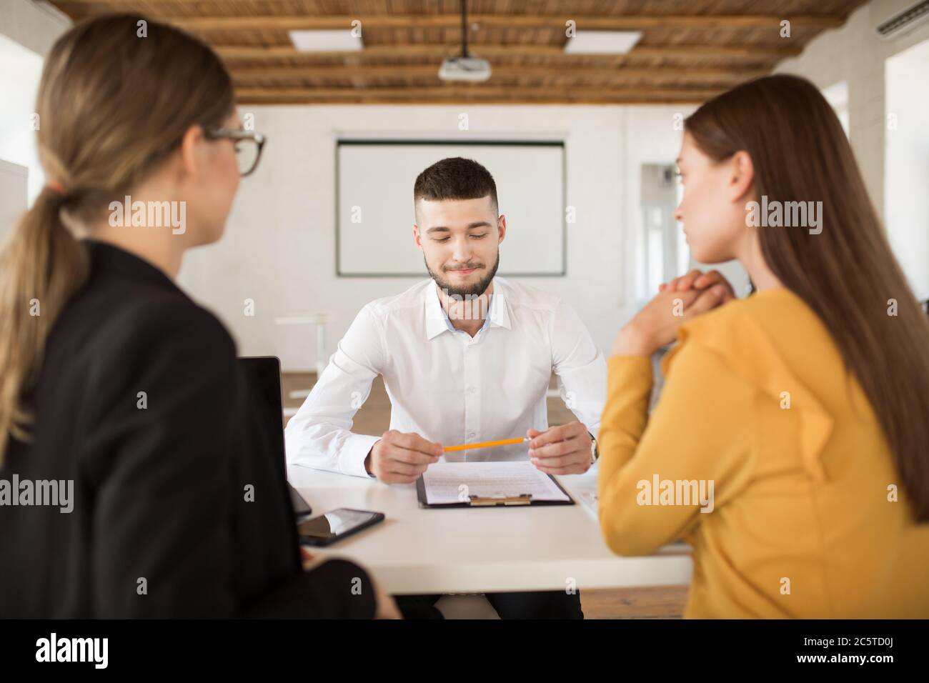 Young smiling man in white shirt holding pencil in hands while waiting ...