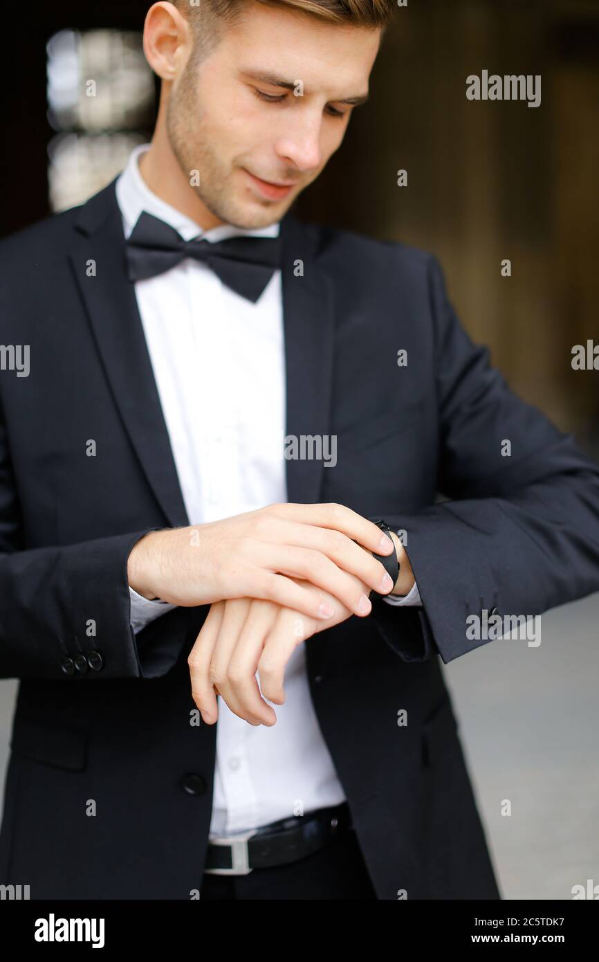 Young man wearing black suit and waiting, loking at watch Stock Photo ...