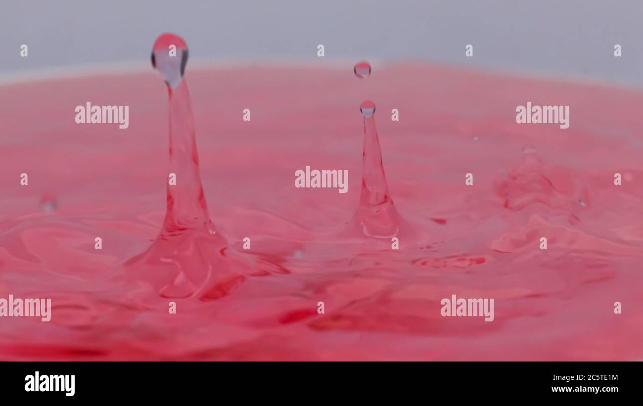 Pink color drop falling and splashing in water, creative forms freezing ...