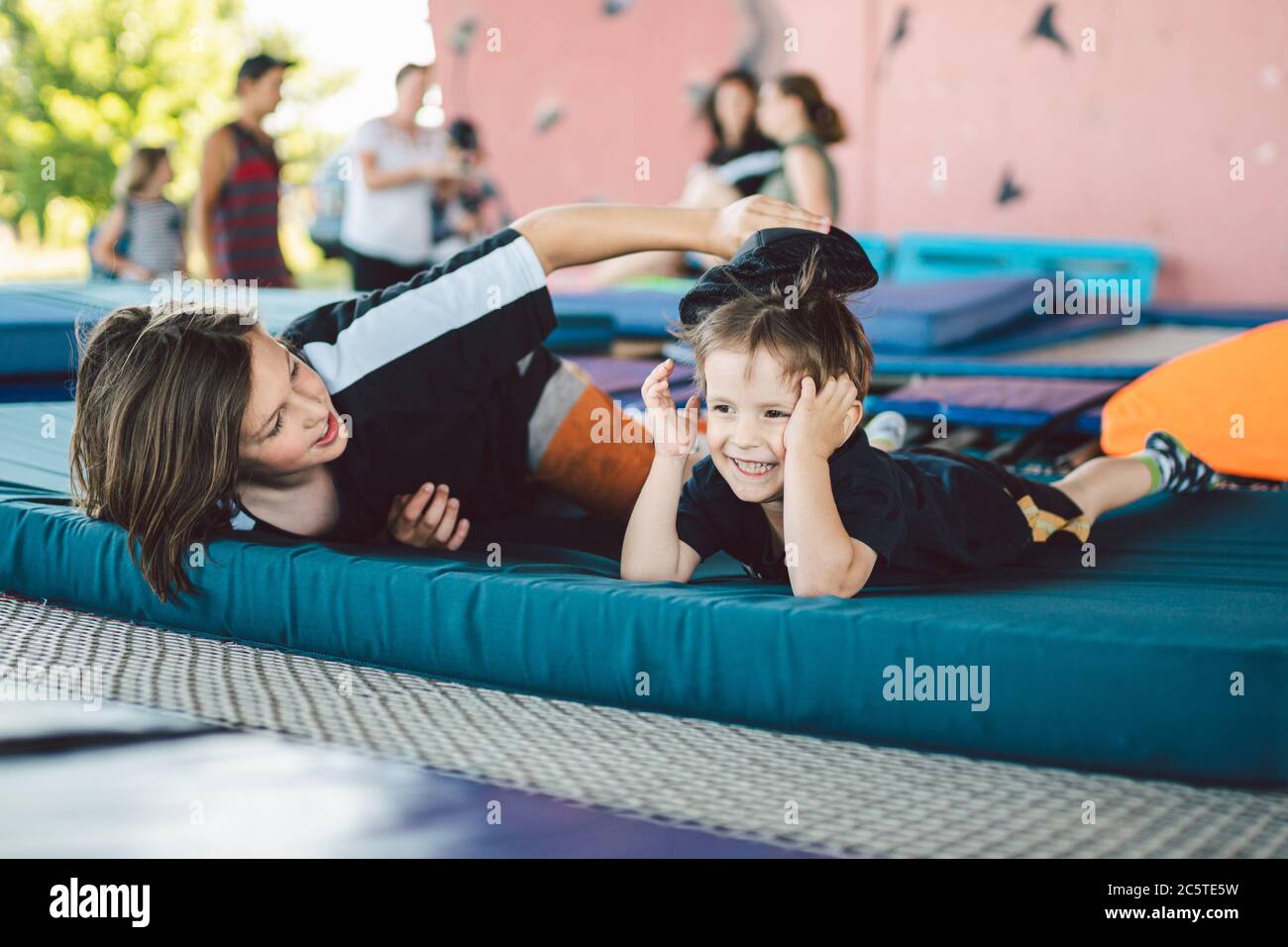 Tired children play lying on sports trampoline. Brothers cuddling on a ...