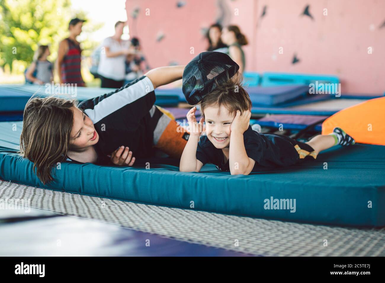 Two brothers have fun lying on trampoline mat in outdoor sports center ...