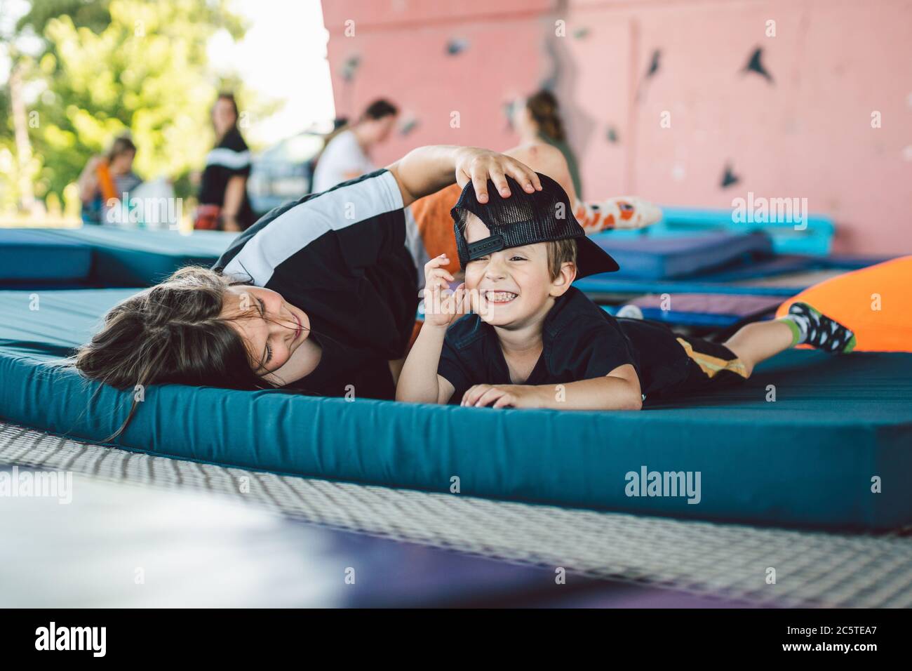 Two brothers have fun lying on trampoline mat in outdoor sports center ...