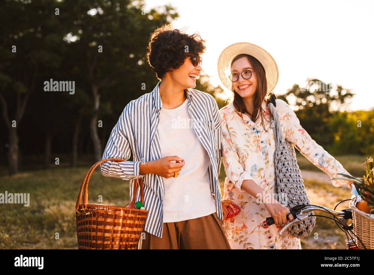 Two beautiful smiling girls with bicycle and basket happily look Stock ...