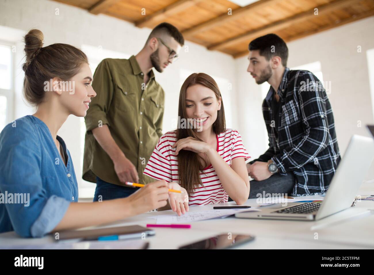 Two pretty girls working together in modern office with colleagues on ...