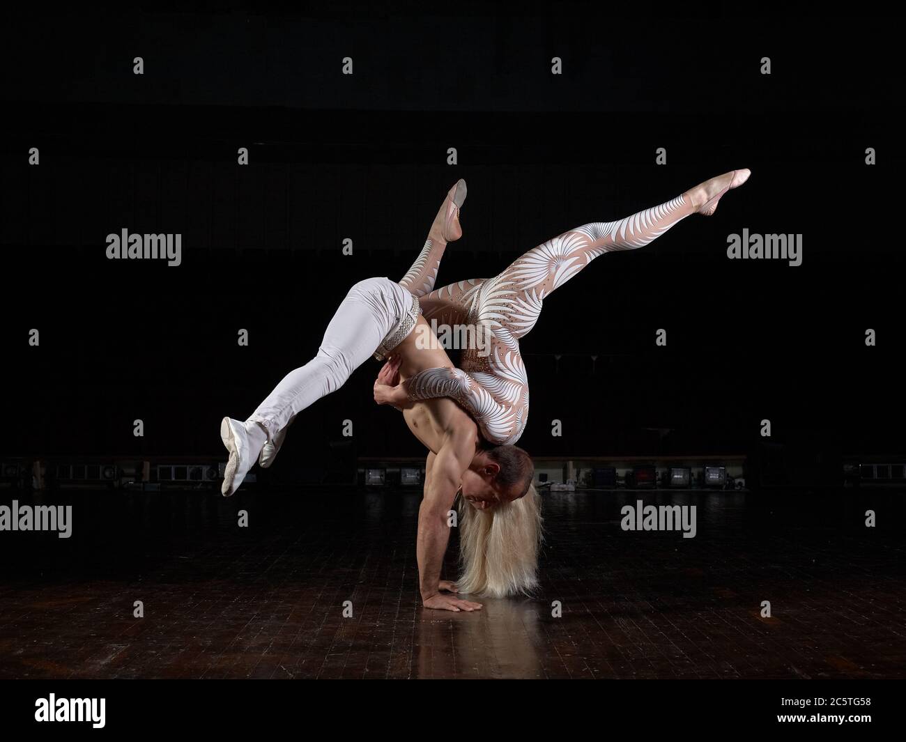 A sports couple of acrobats performs the trick. Acrobats on a dark ...