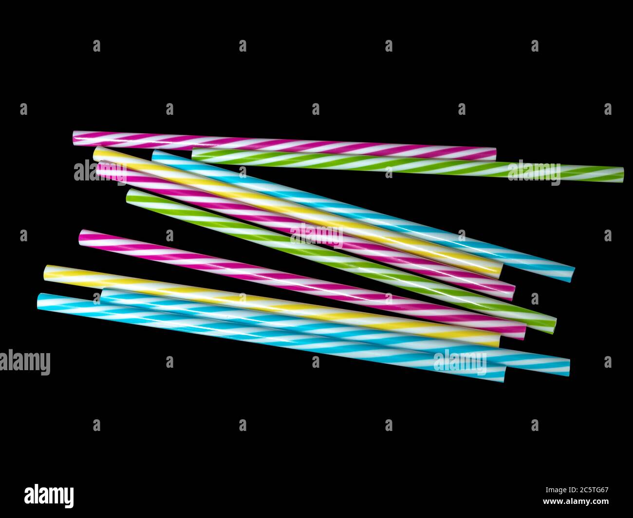 Piles of colorful striped plastic drinking straw, black underground ...