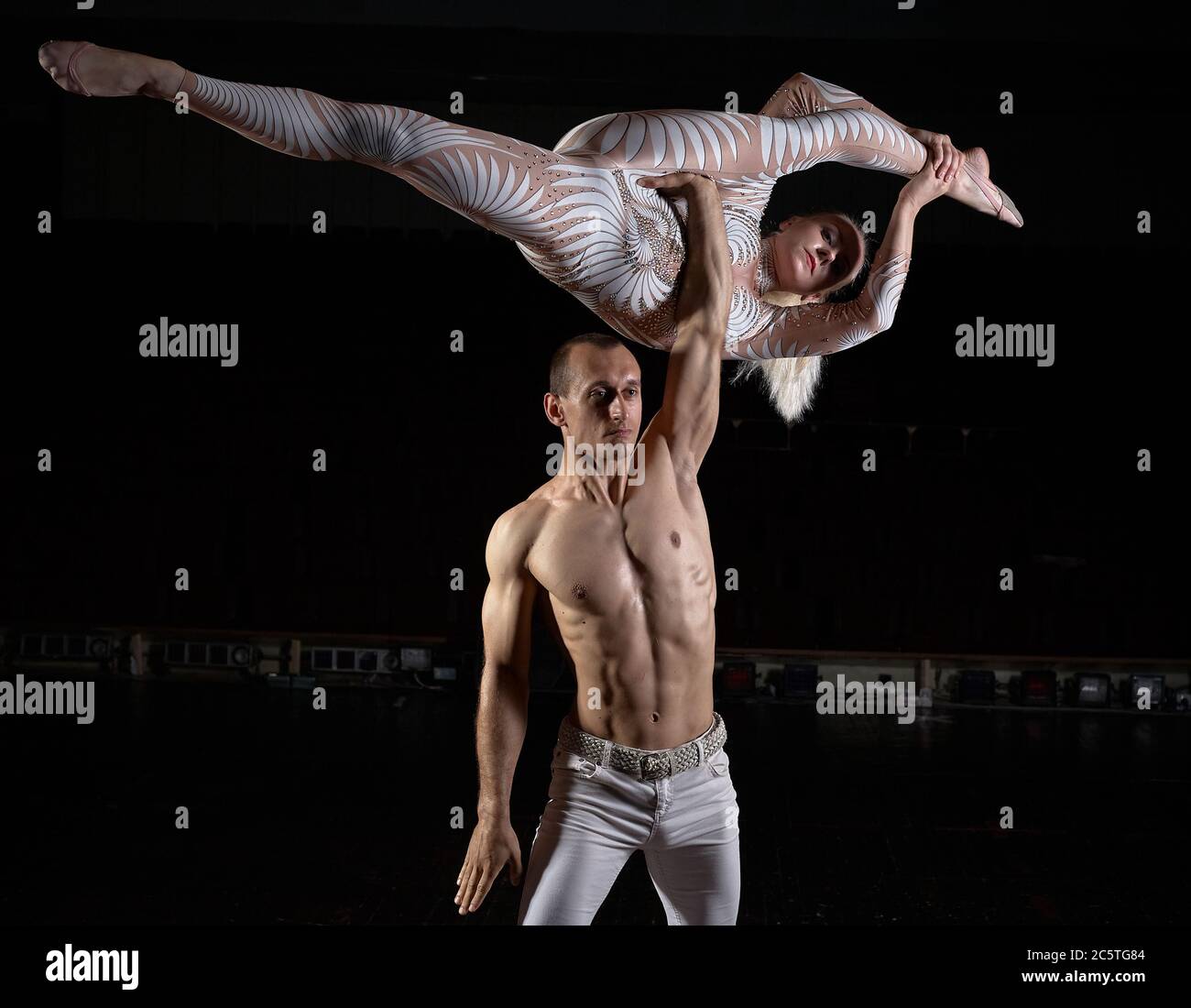 A sports couple of acrobats performs the trick. Acrobats on a dark ...
