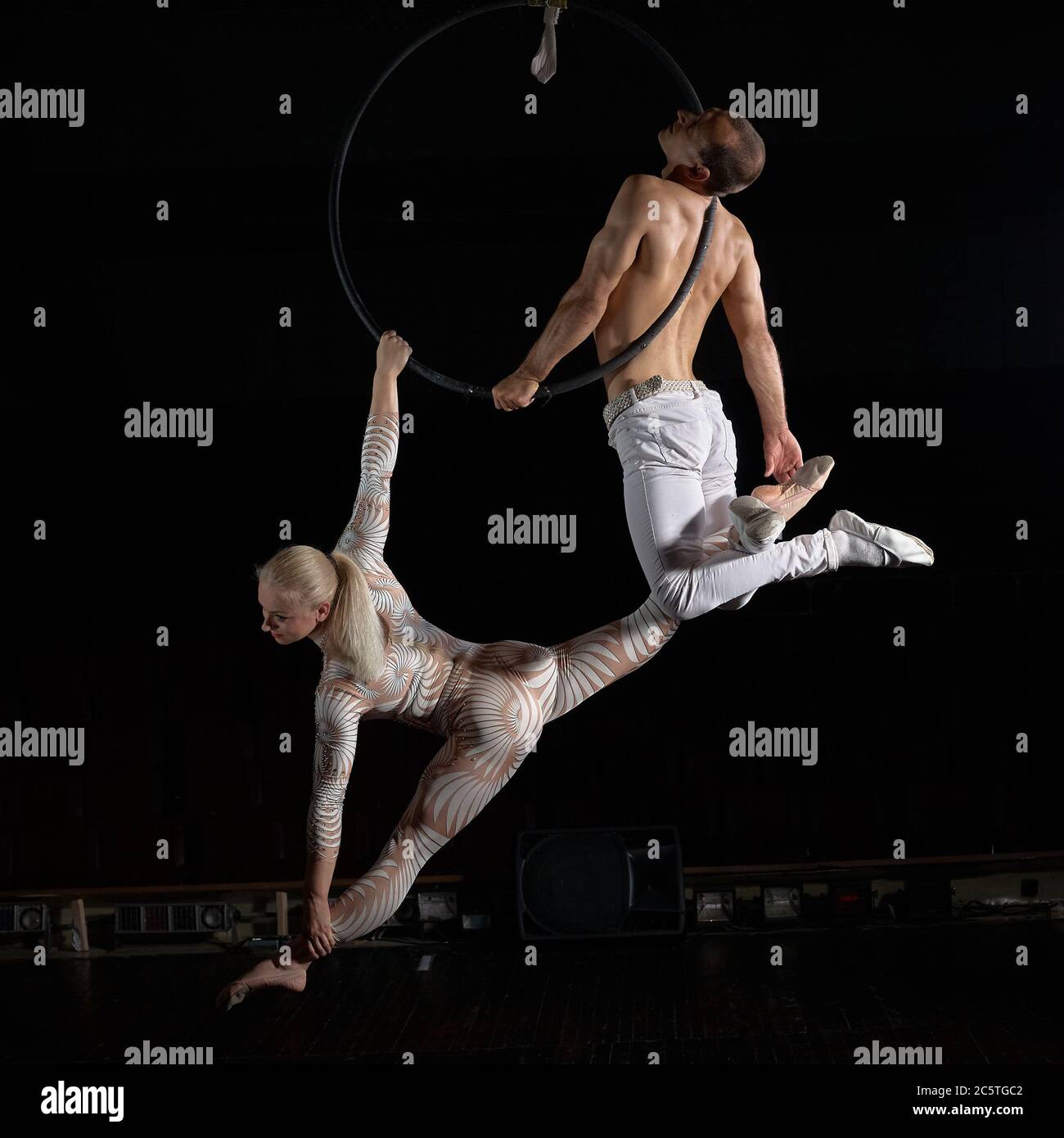 A sports acrobat couple performs a trick in the air. Acrobats on a dark ...