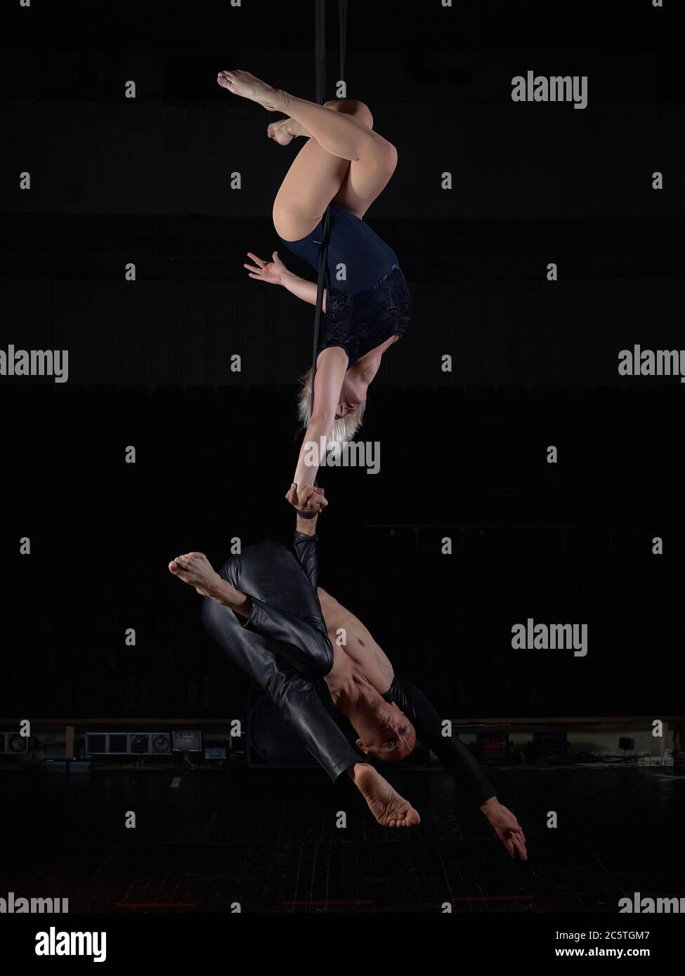 A sports acrobat couple performs a trick in the air. Acrobats on a dark ...
