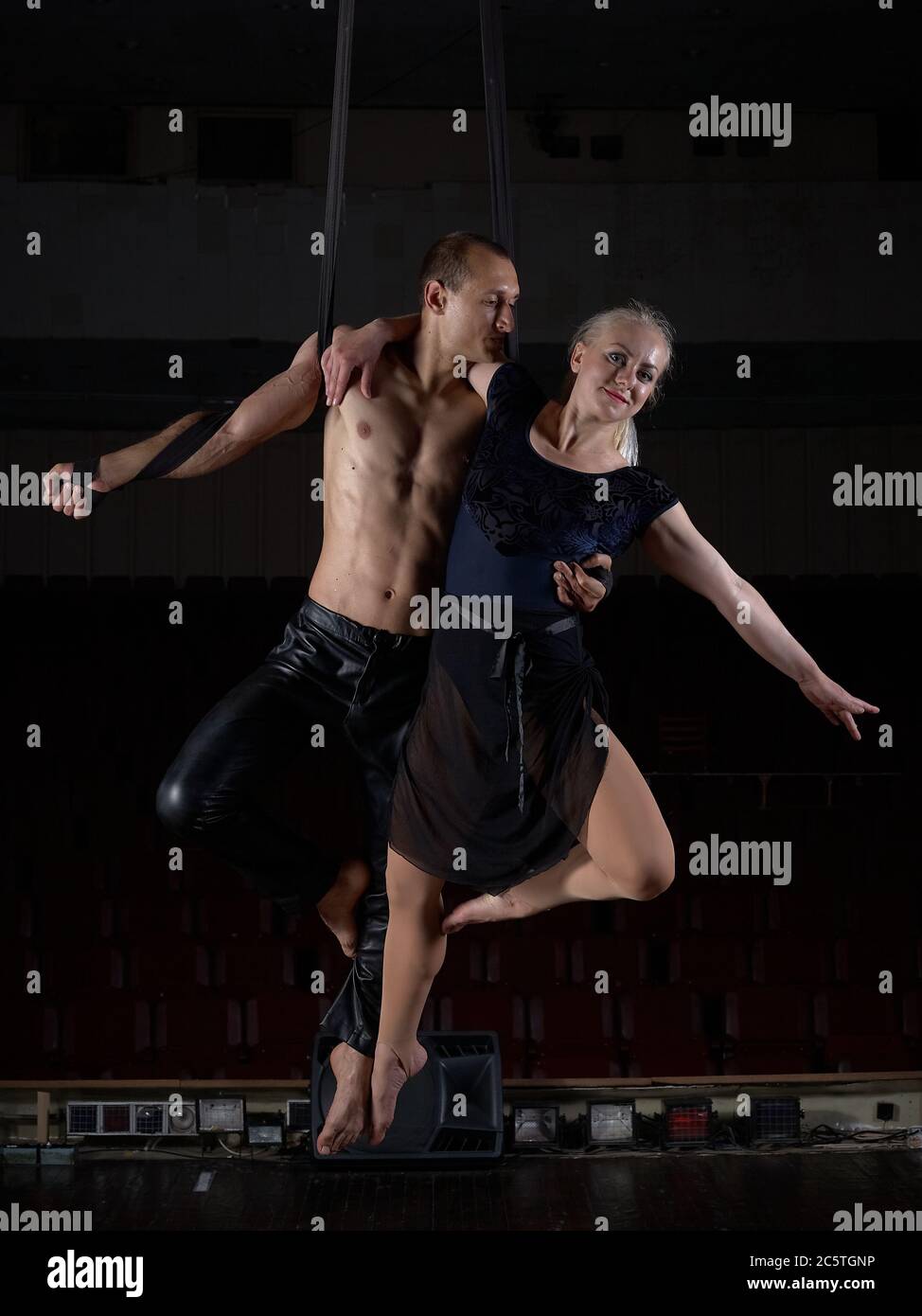 A sports acrobat couple performs a trick in the air. Acrobats on a dark ...