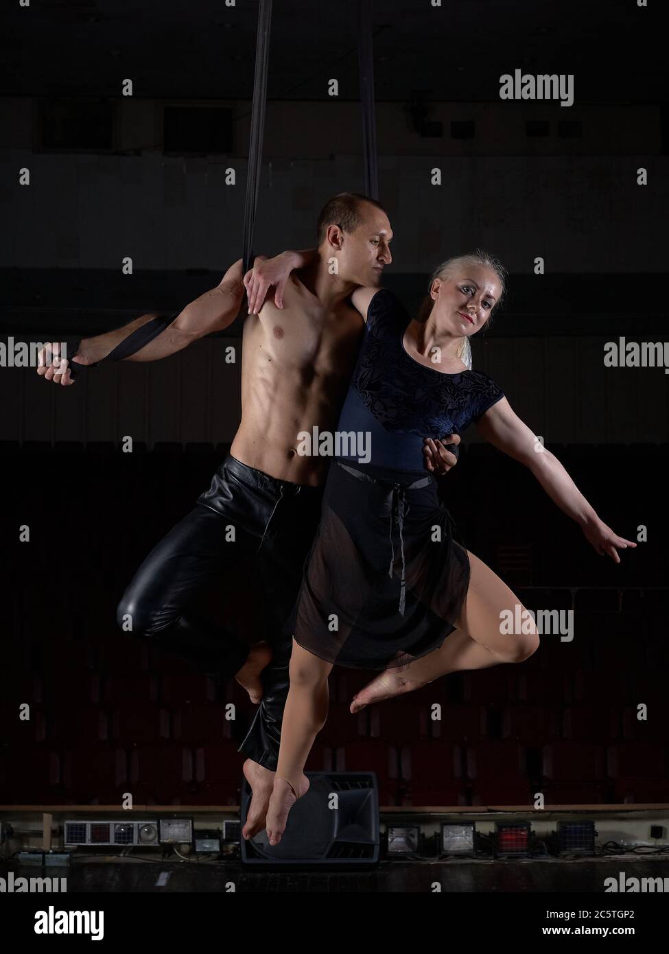 A sports acrobat couple performs a trick in the air. Acrobats on a dark ...
