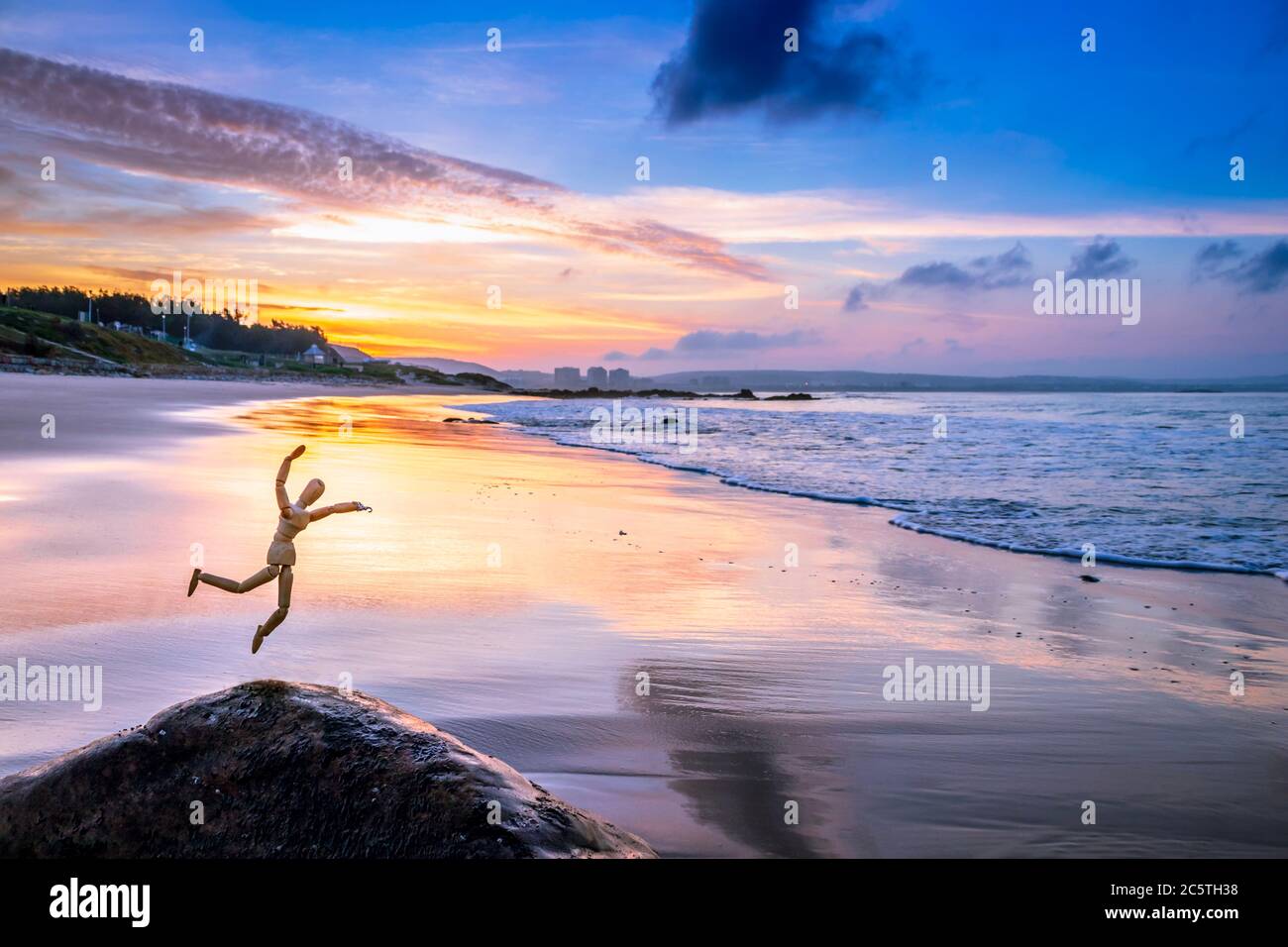 Wooden Human Manikin posing on beach with a view of a beautiful cloudy ...